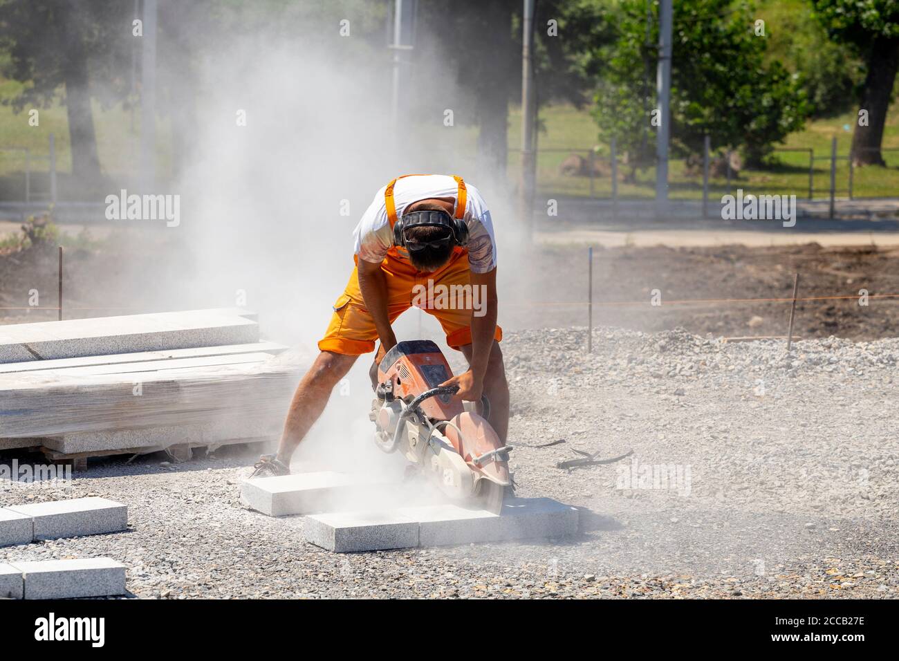 Worker cutting granit stone with circular hand saw at construction site ...