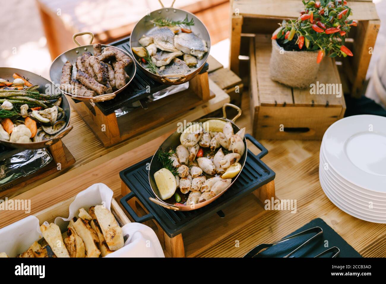 Hot pans with cooked food on a cast-iron stove on a wooden table with a ...