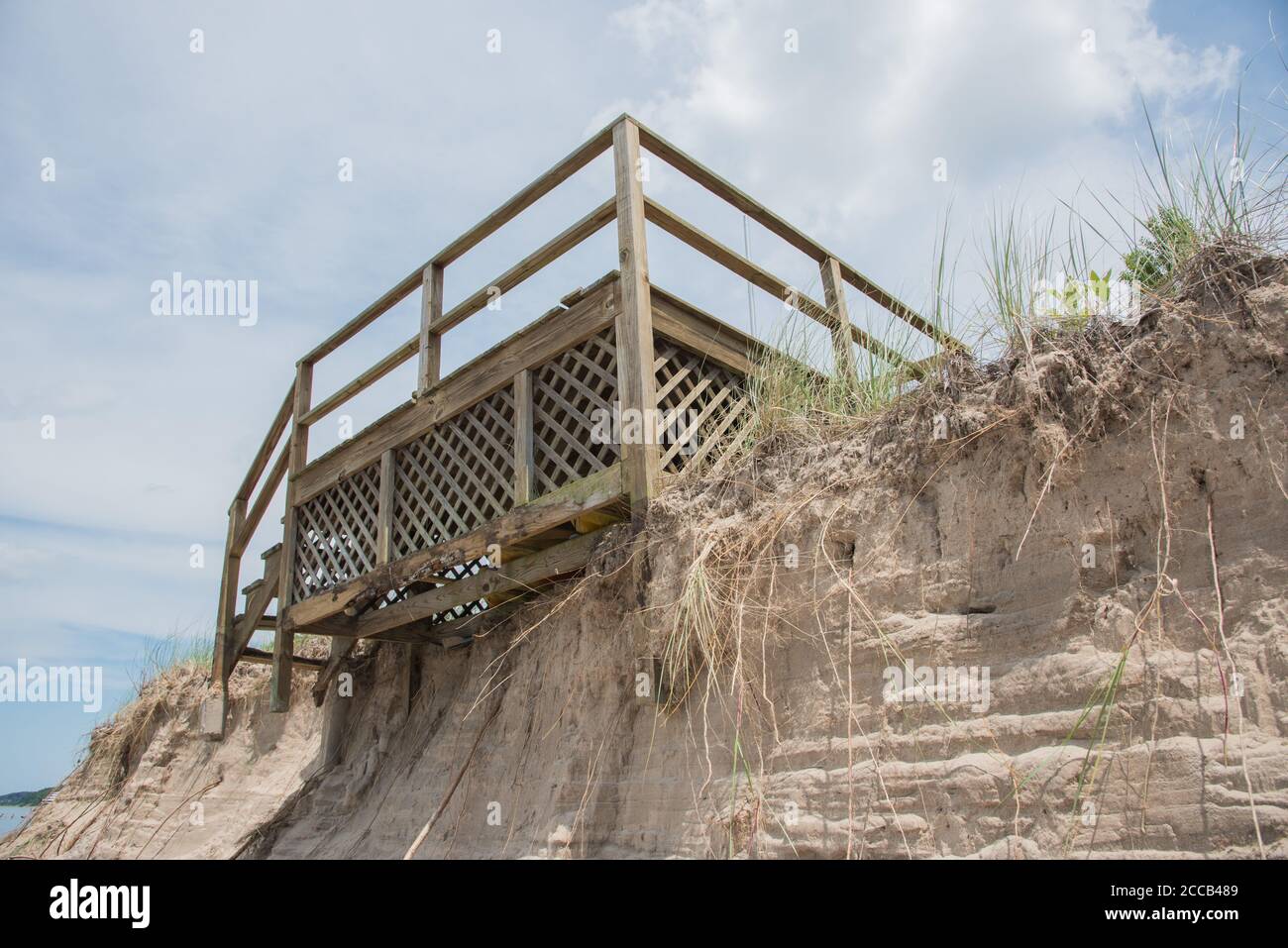 Unsafe beach access stairs hanging off edge of eroded dunes from storm ...