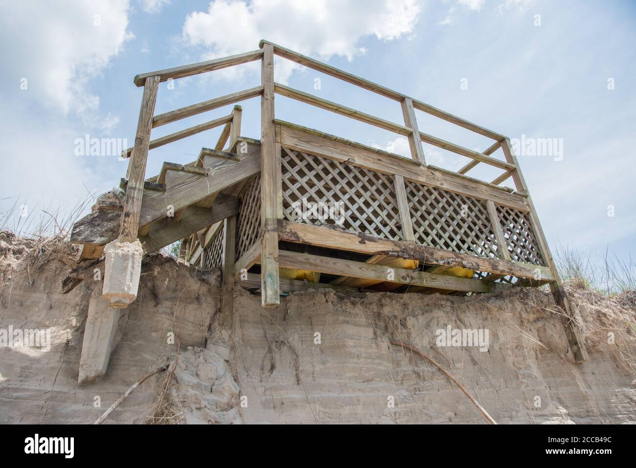 Unsafe beach access stairs hanging off edge of eroded dunes from storm ...