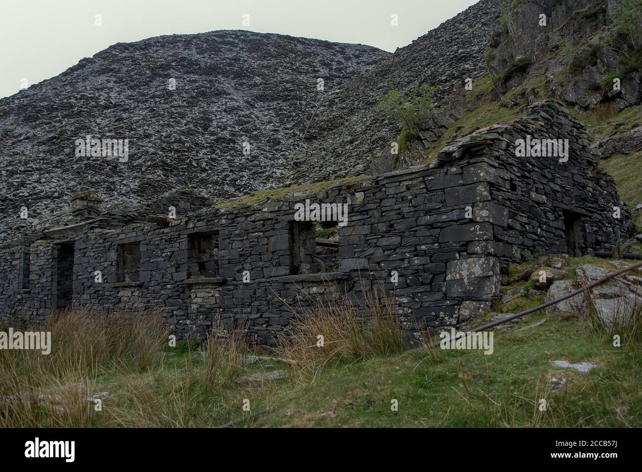 Old slate house by a mountain of slate in the British highlands Stock ...