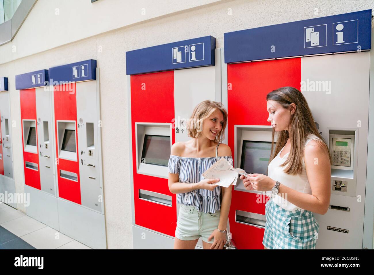 Two girls with tickets purchased in a red vending machine Stock Photo ...