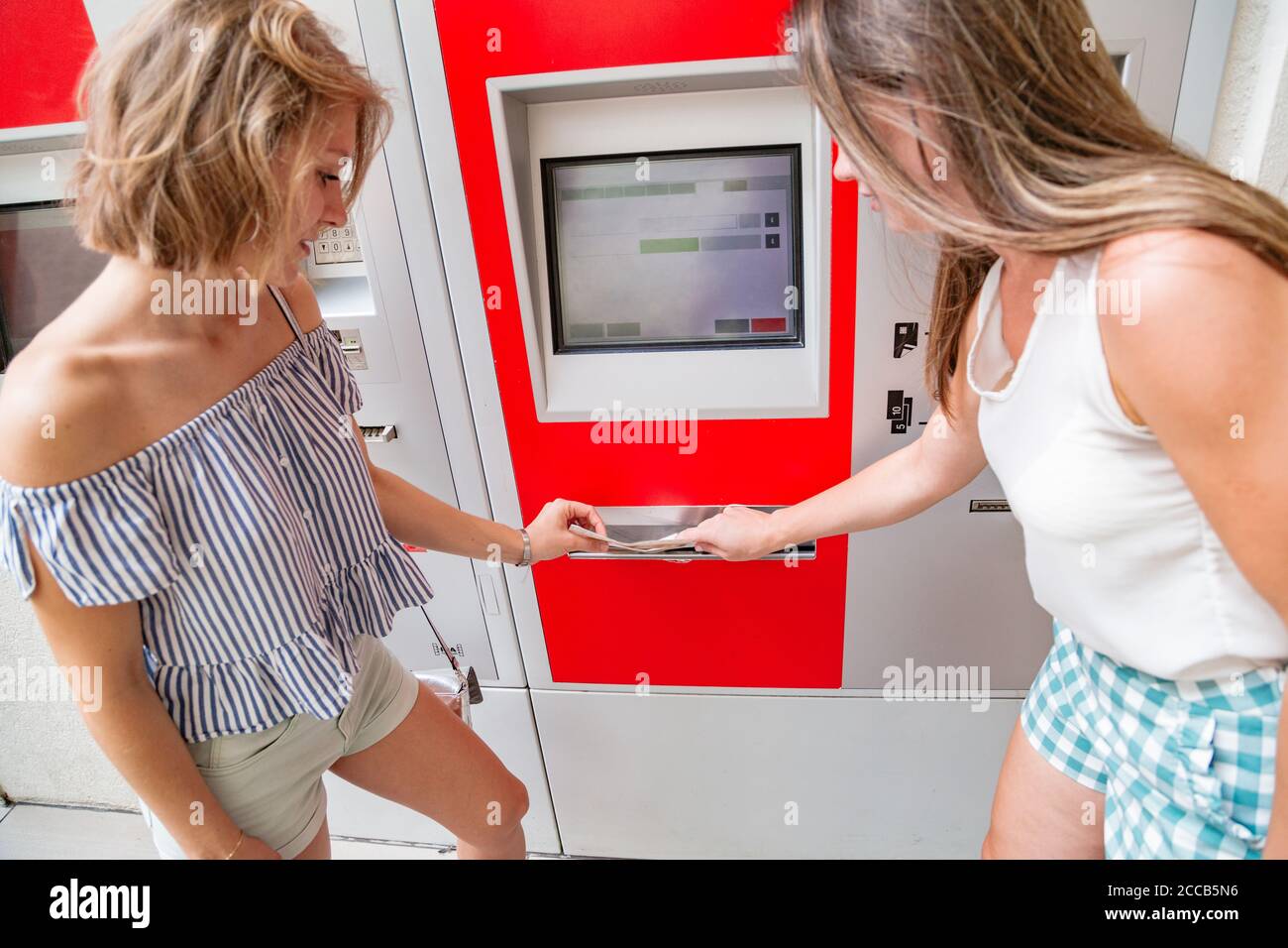 Girls taking tickets from a ticket machine Stock Photo - Alamy