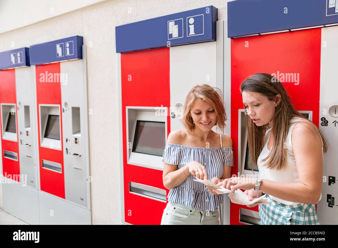 Two girls with tickets purchased in a red vending machine Stock Photo ...