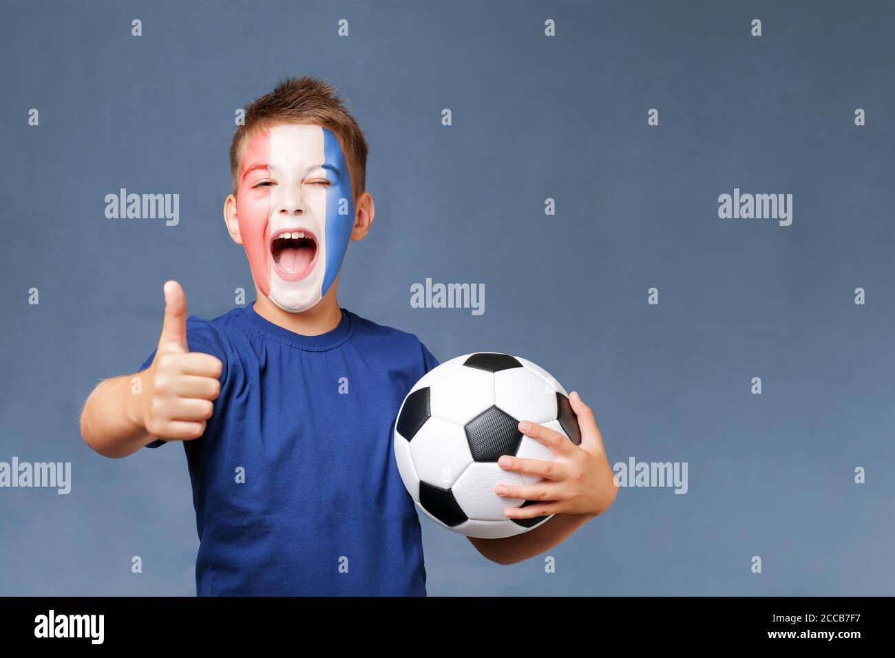 Handsome screaming french fanboy holds soccer ball and gesturing thumbs ...