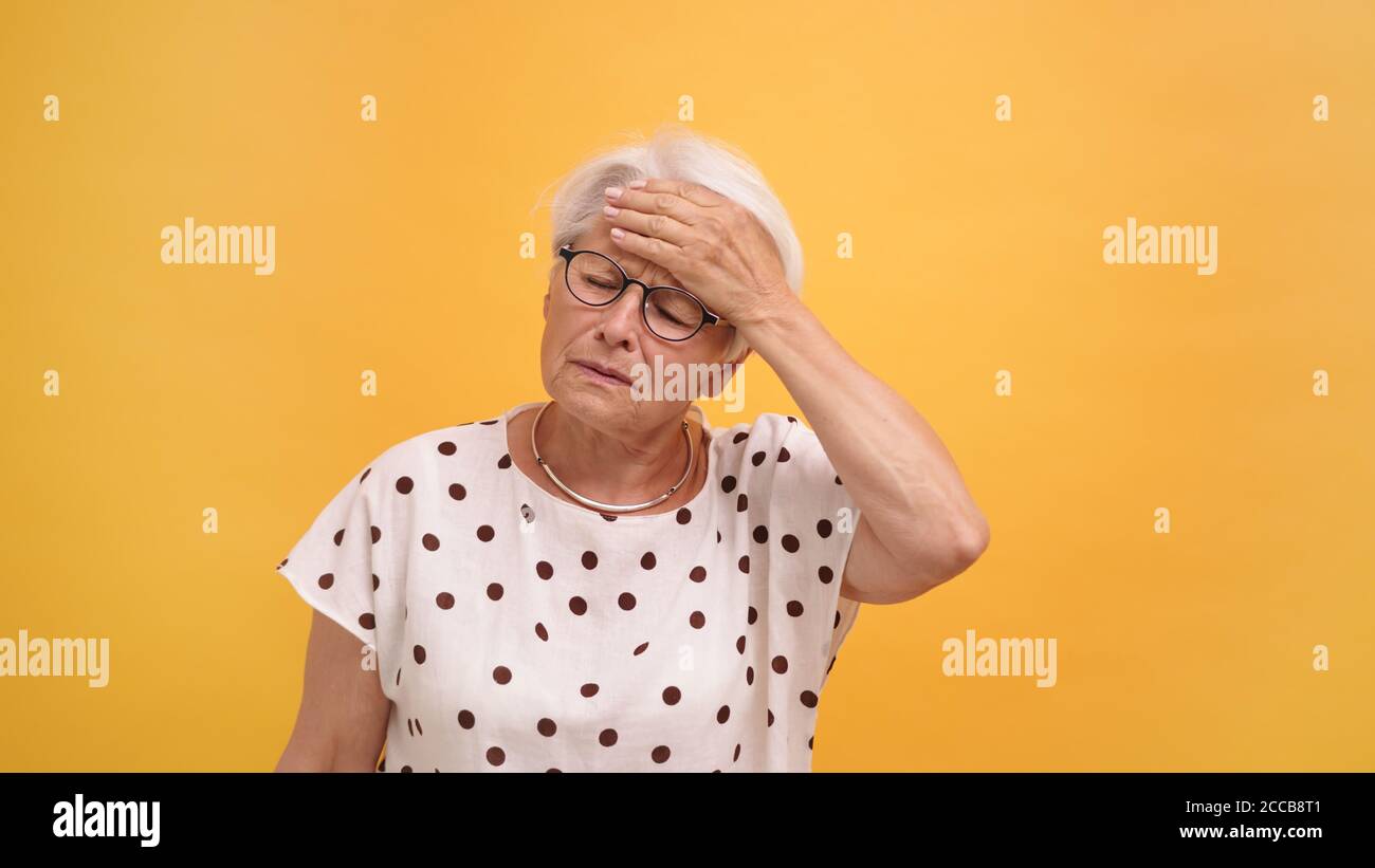 senior woman having a strong headache. Putting hand over her forehead ...