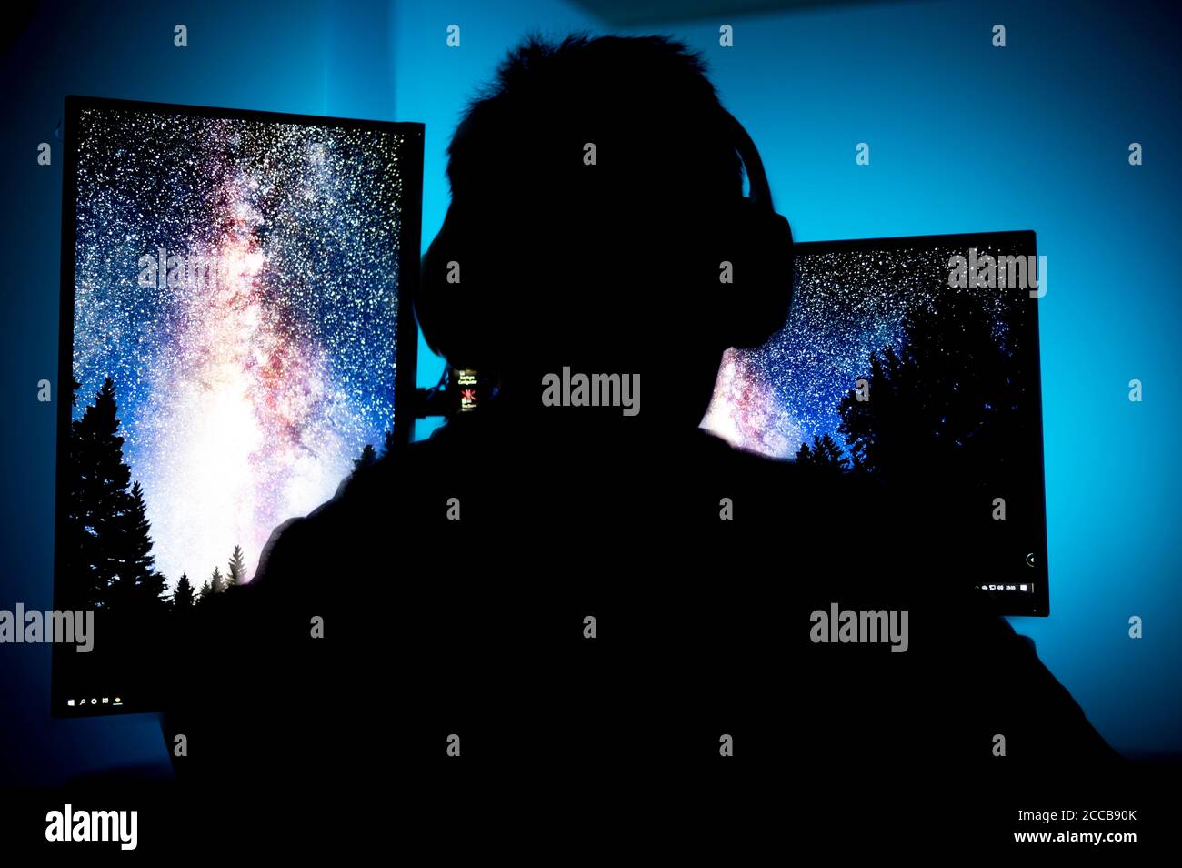 Male Sat on computer with dual screen with desktop background Stock ...