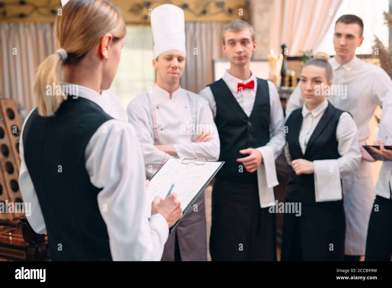 restaurant manager and his staff in kitchen. interacting to head chef ...