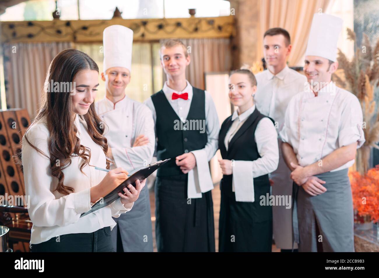 restaurant manager and his staff in kitchen. interacting to head chef ...