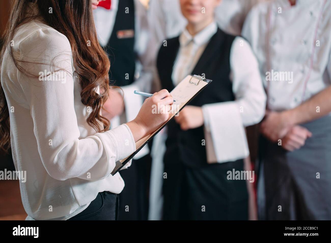 restaurant manager and his staff in kitchen. interacting to head chef ...