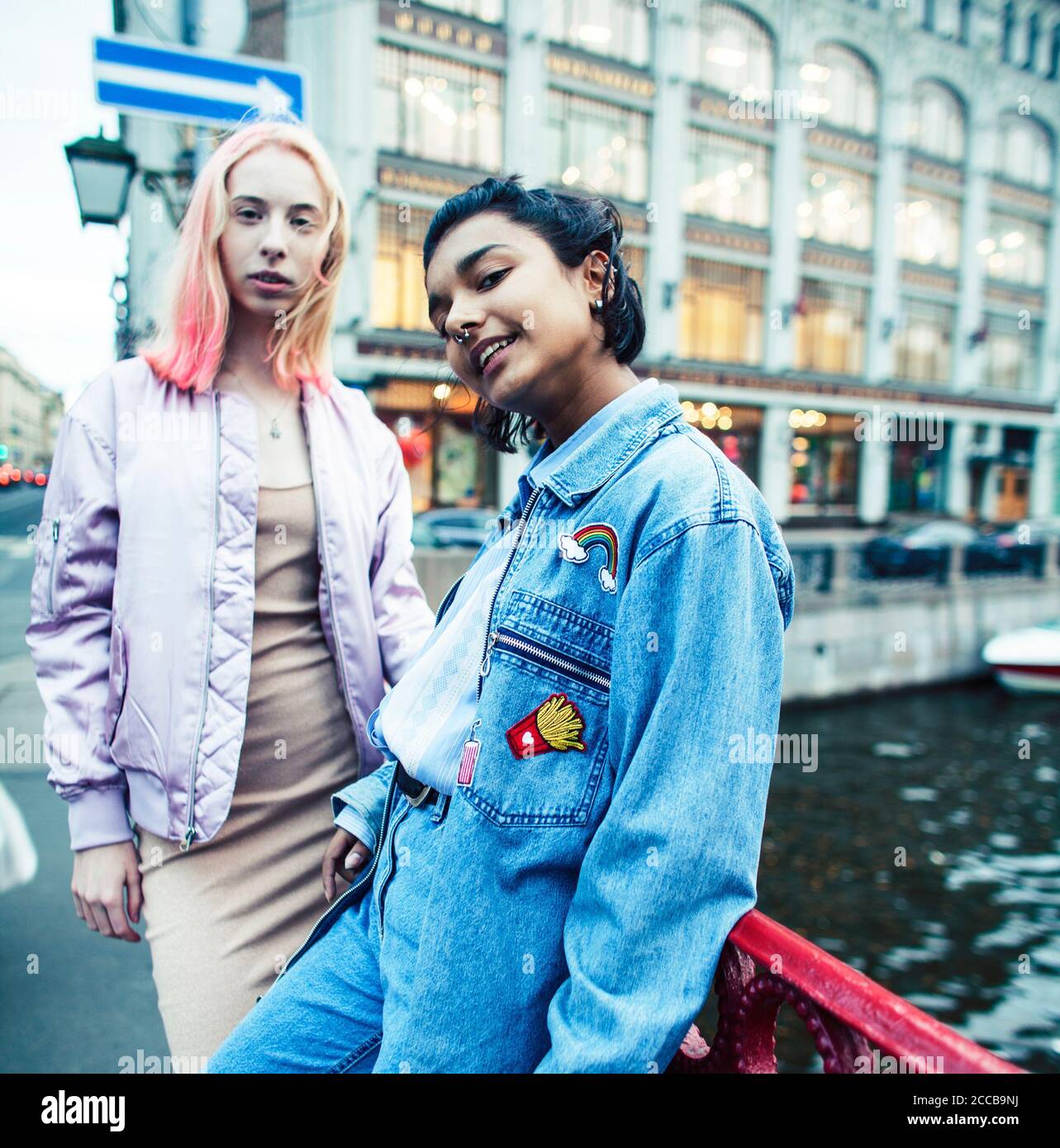 Two teenage girls infront of university building smiling, having fun ...