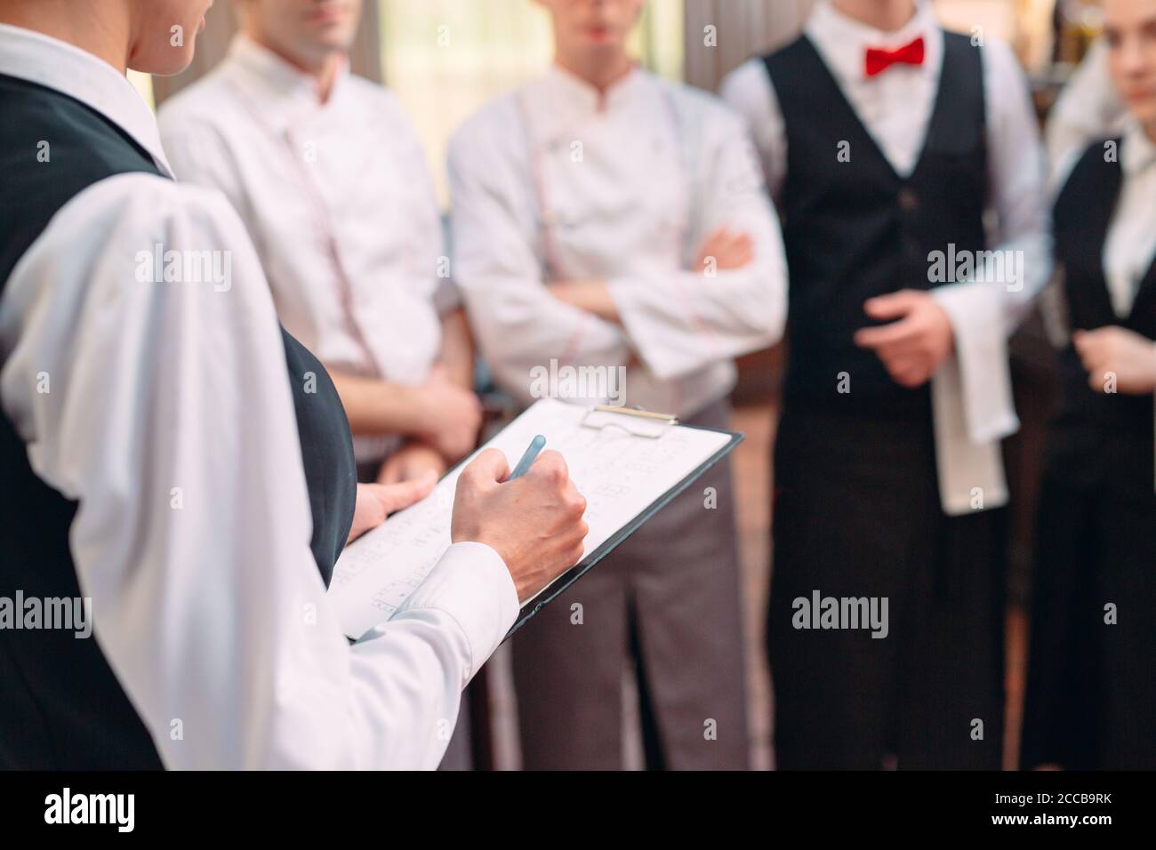 restaurant manager and his staff in kitchen. interacting to head chef ...