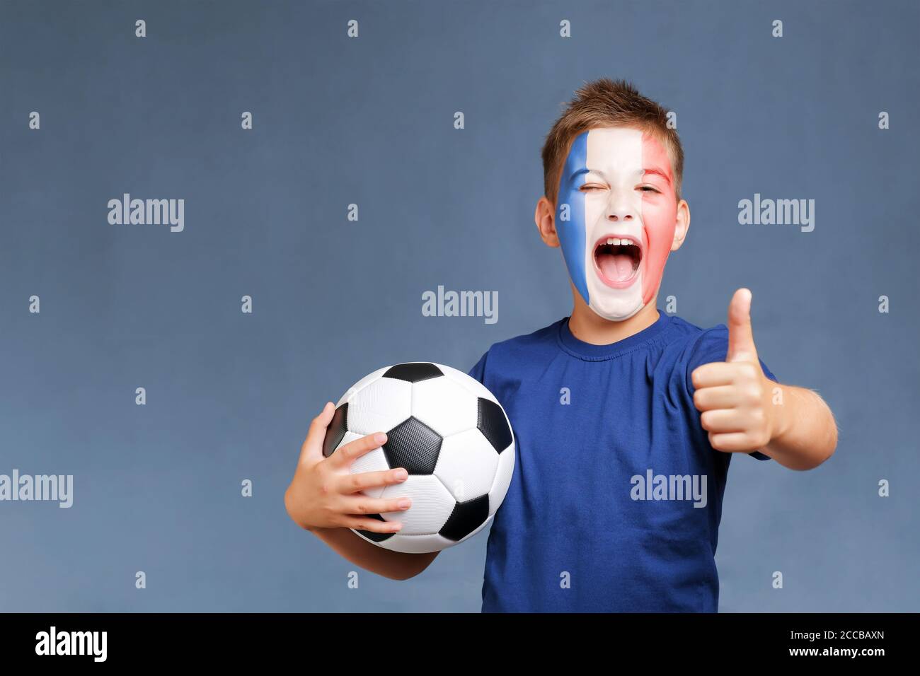 Handsome screaming french fanboy holds soccer ball and gesturing thumbs ...