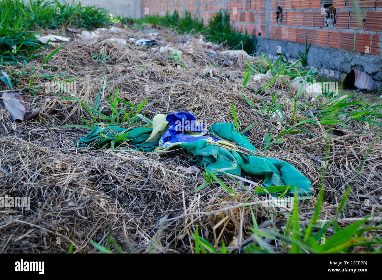 torn, dirty and rolled-up Brazilian flag thrown through trash on empty ...