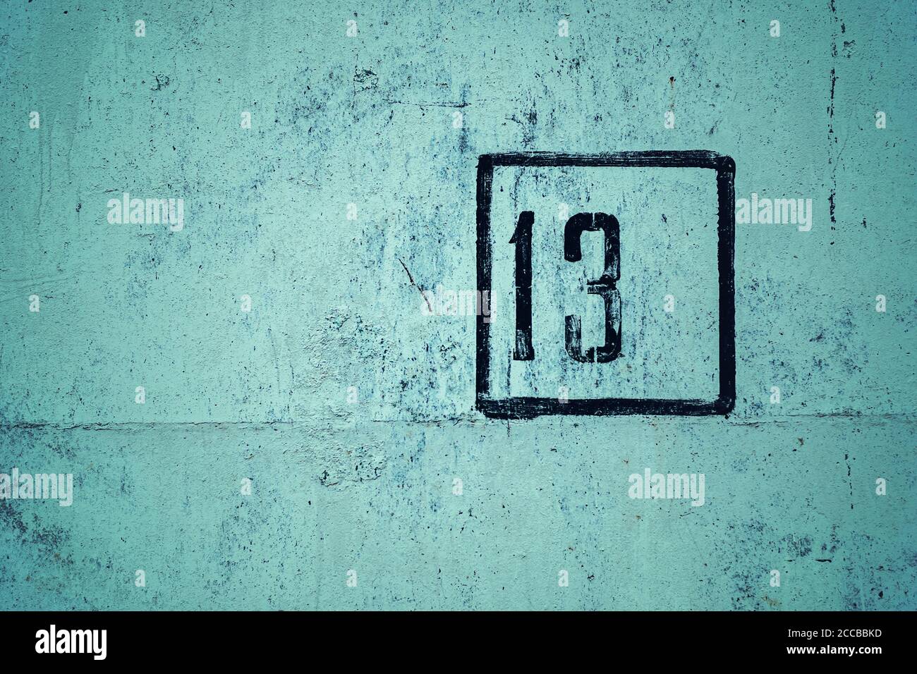 number 13 is stenciled in black frame on green concrete wall, copy ...