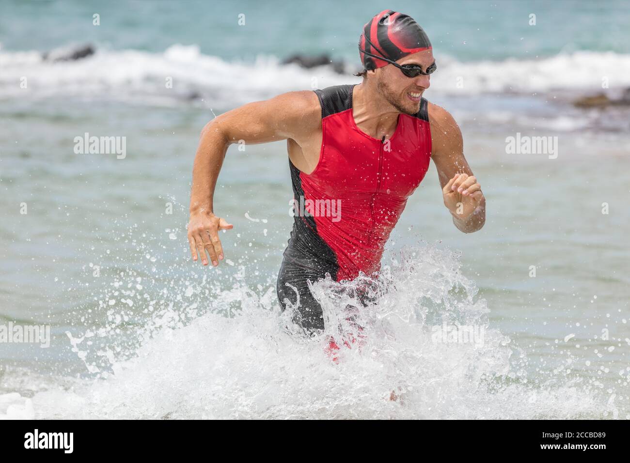 Triathlon swimming man. Male triathlete swimmer running out of ocean ...