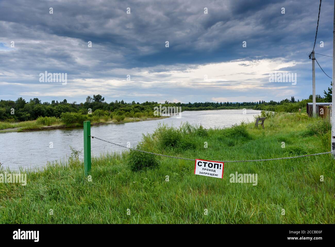 Green lawn near the river in the forest and a barrier stop passage is ...