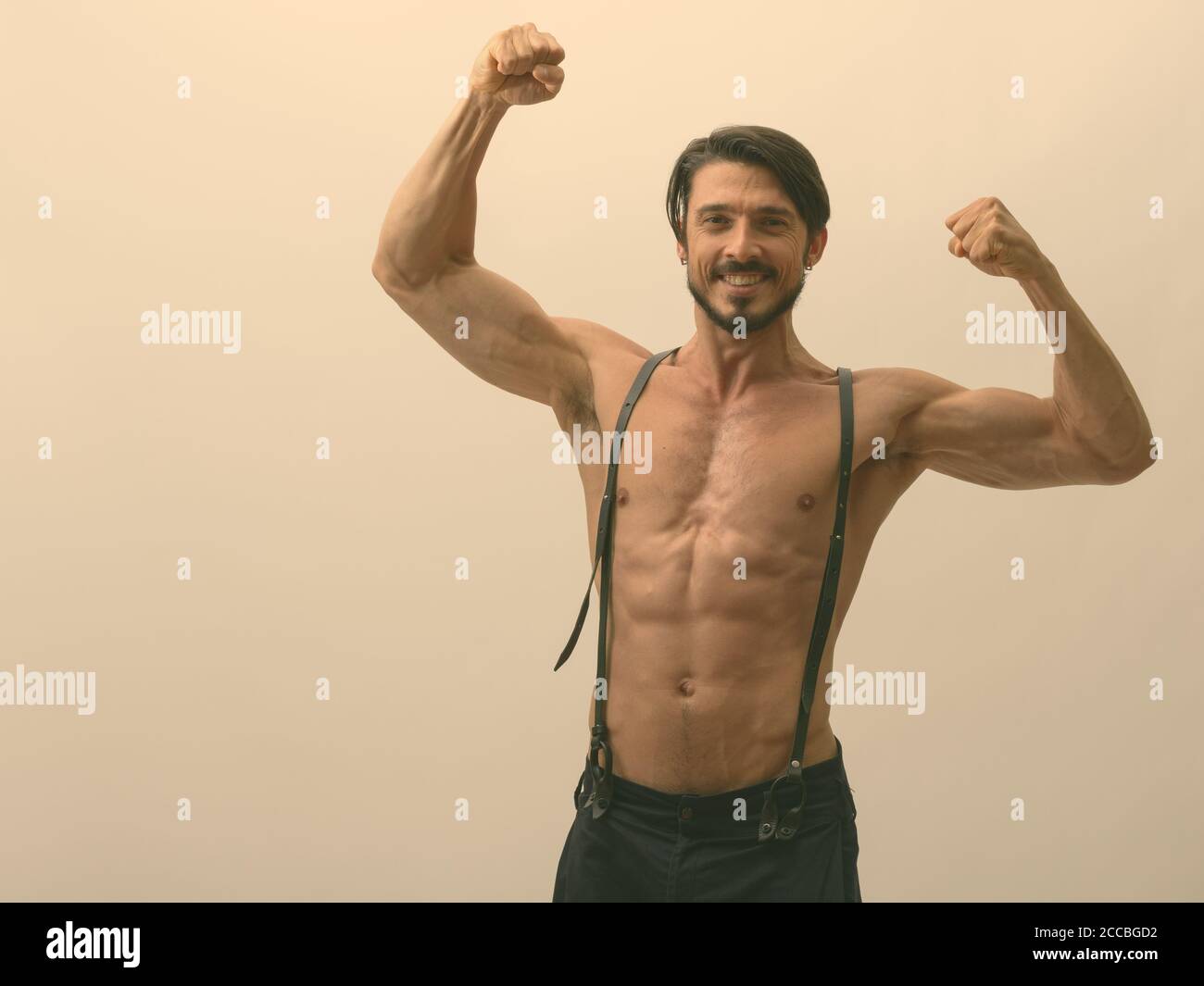 Studio shot of happy handsome man smiling and flexing both arms ...