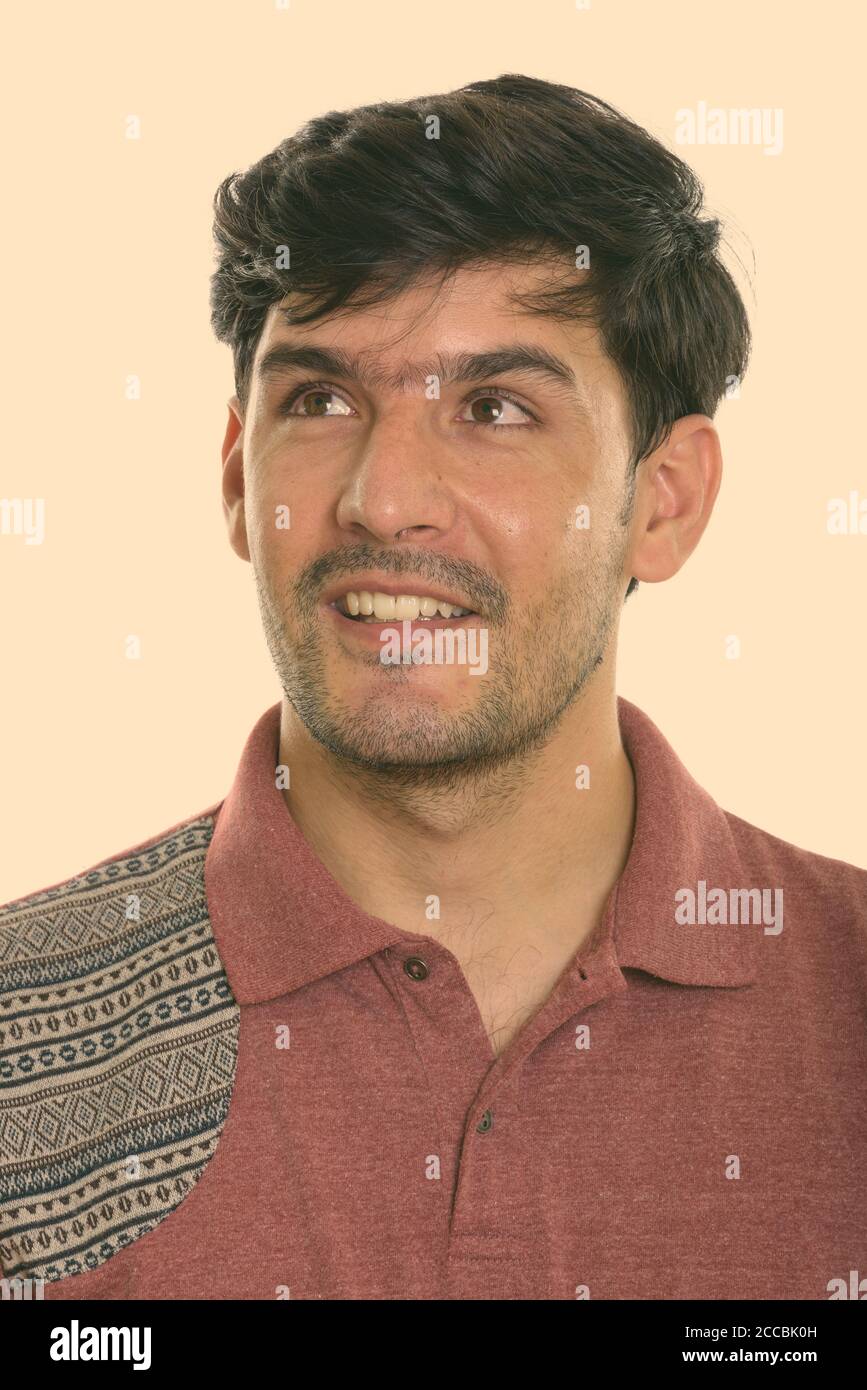 Face of young happy Persian man smiling and thinking while looking up ...