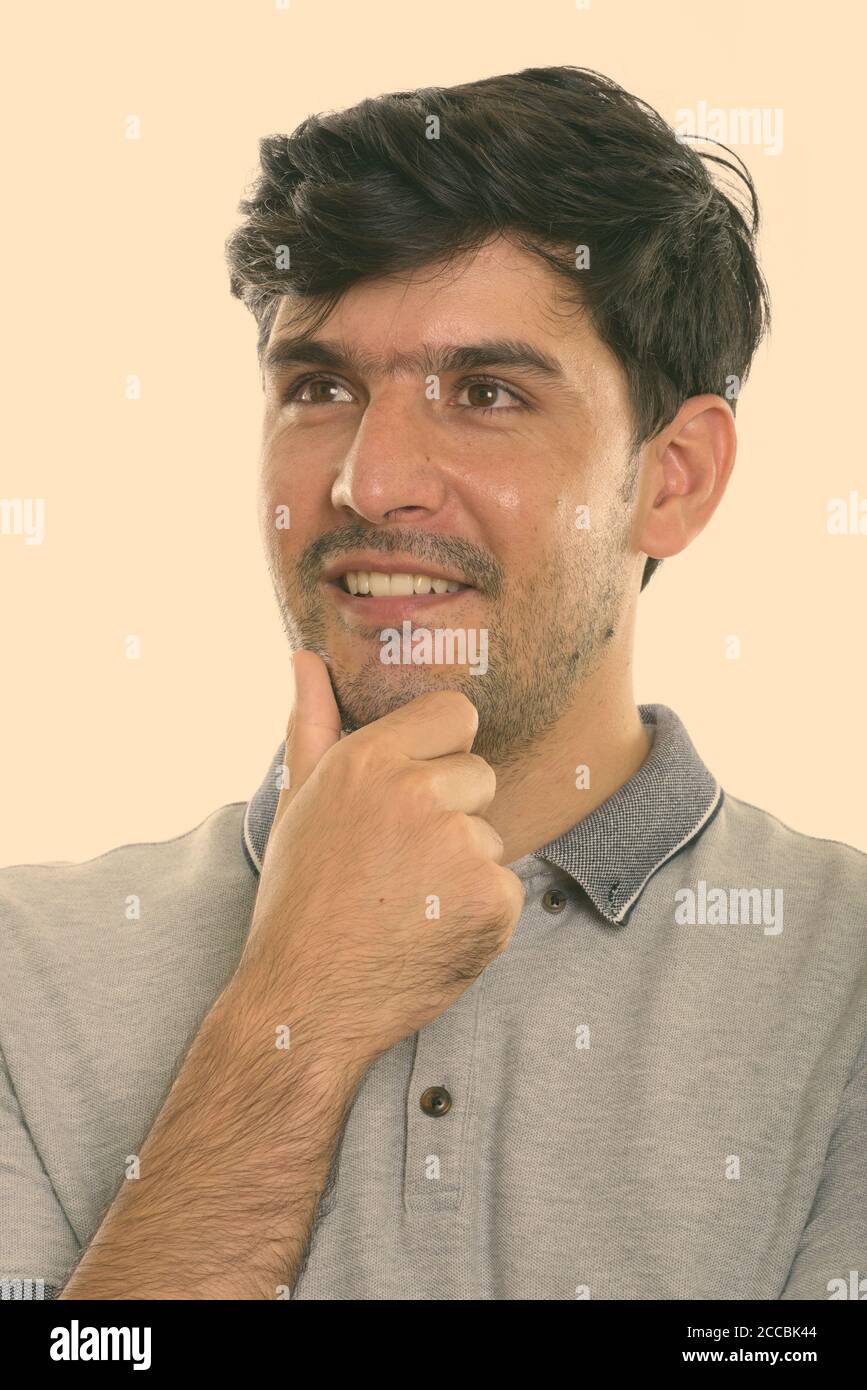 Face of young happy Persian man smiling and thinking while looking up ...