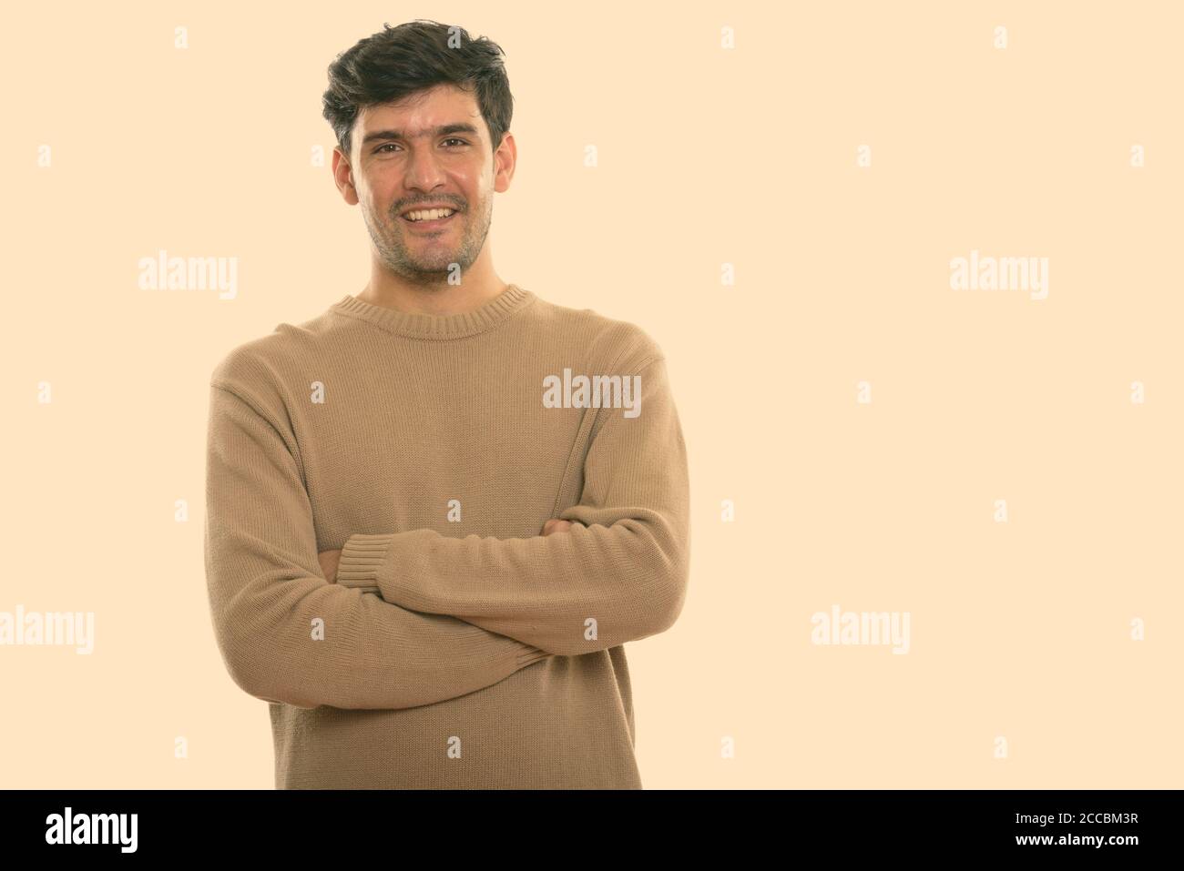 Studio shot of young happy Persian man smiling with arms crossed Stock ...