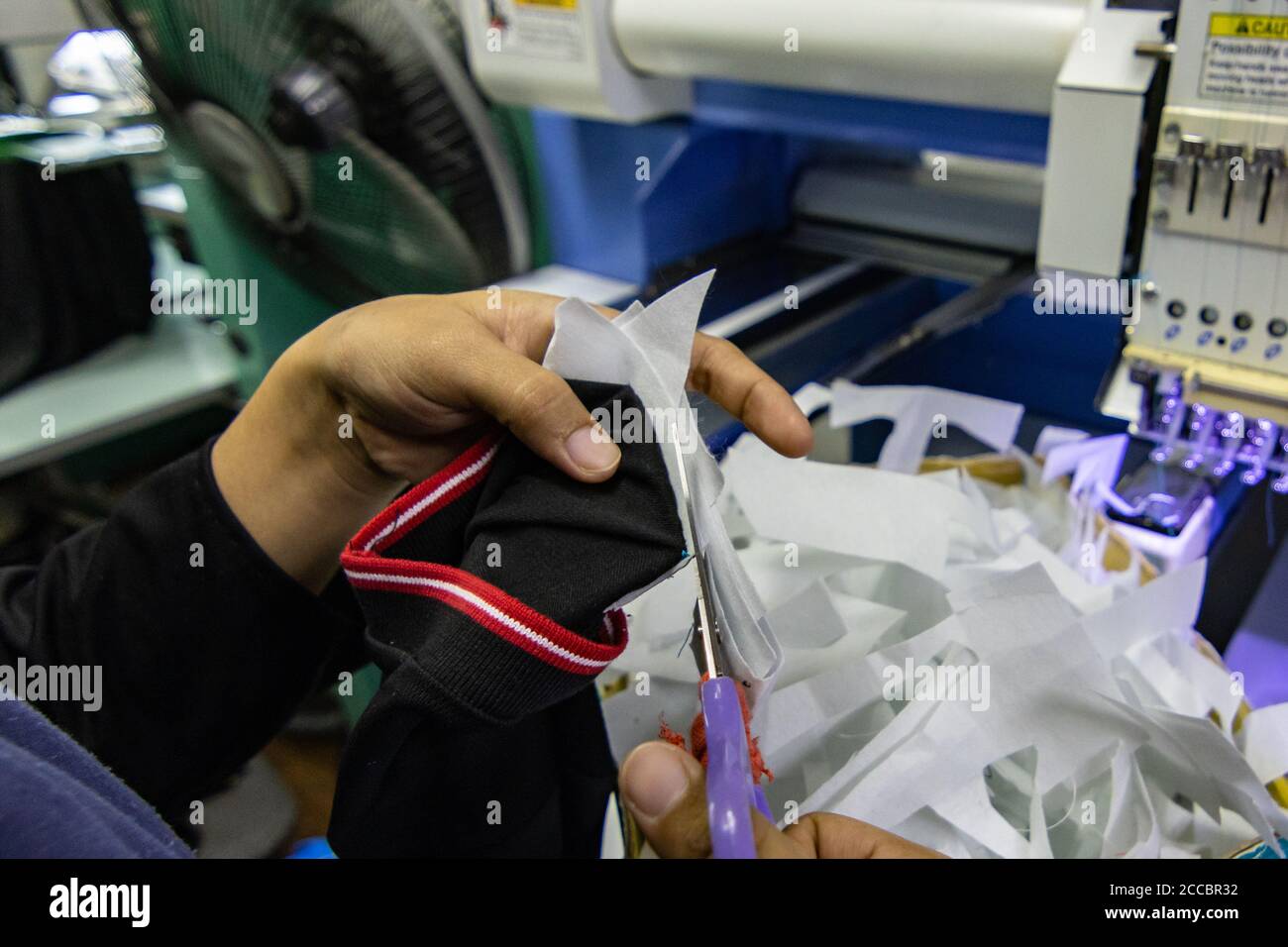 Female worker hand cutting lining paper on staff uniform on Garment ...