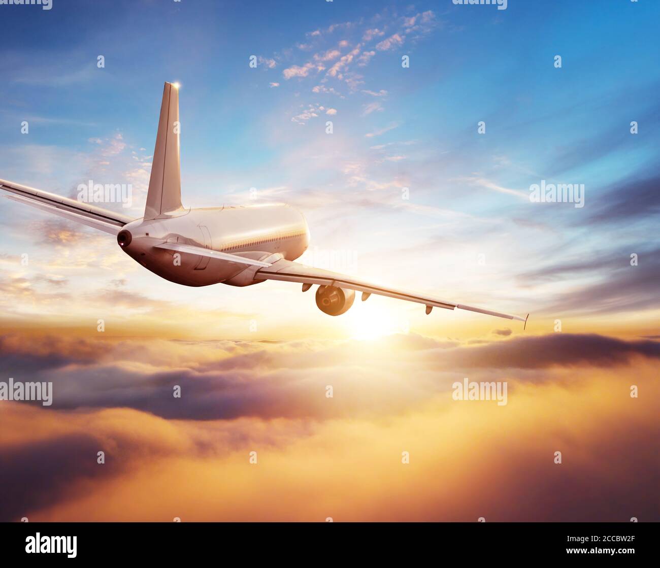 Passengers commercial airplane flying above clouds in sunset light ...