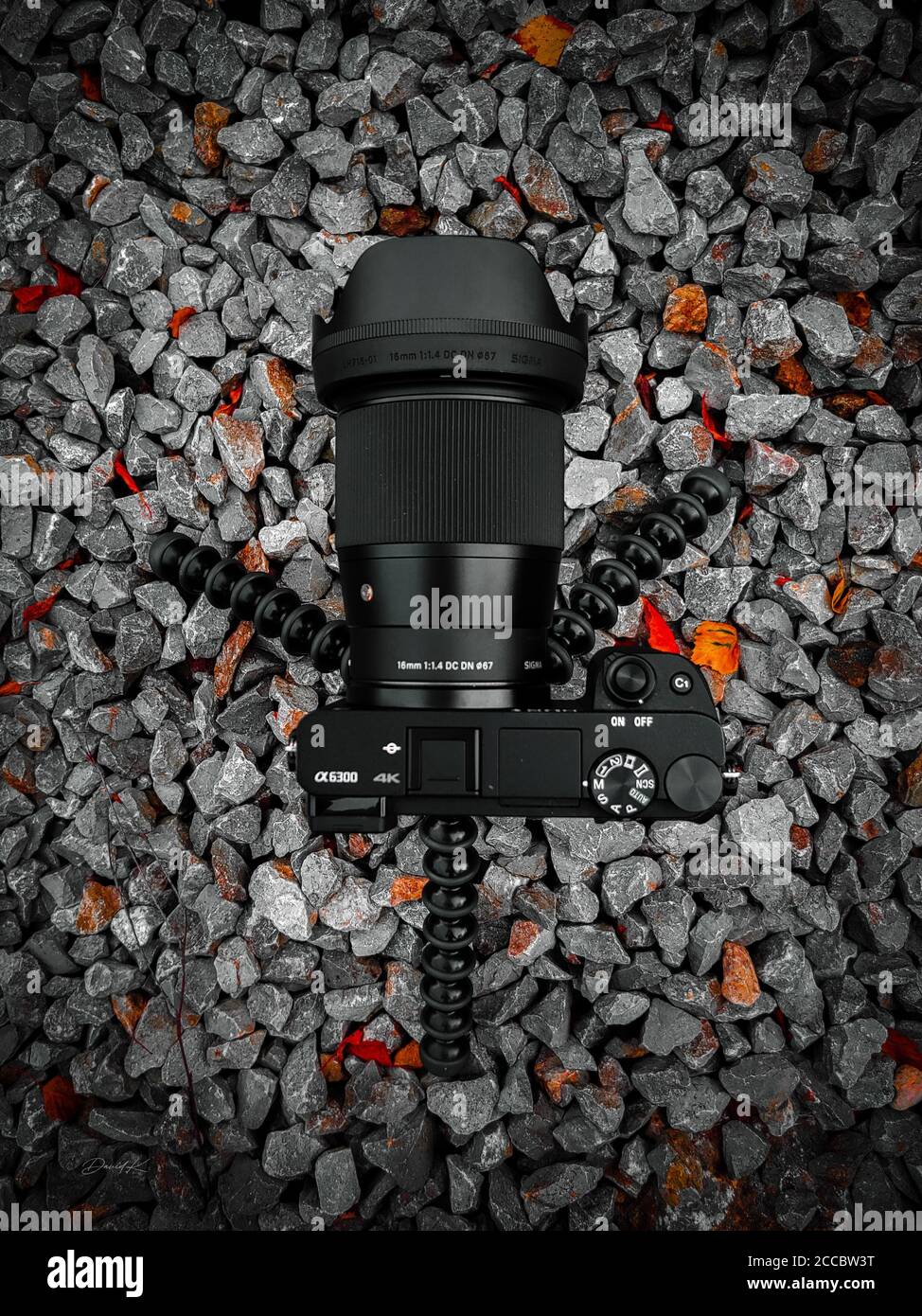 Vertical overhead shot of a DSLR camera on a tripod against gravel ...