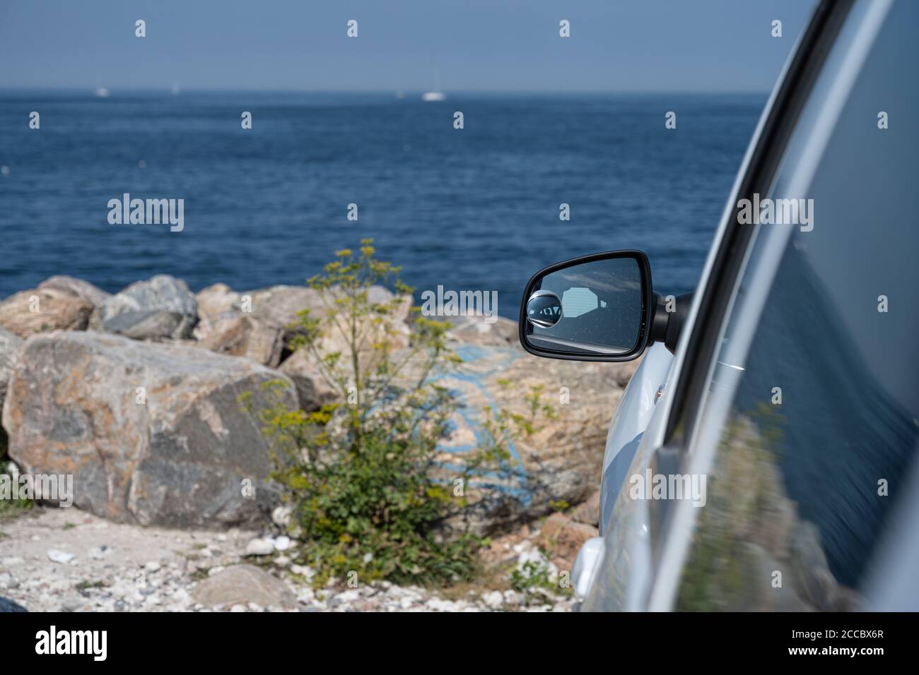 A car parked with ocean view. Water reflections in the car window. View ...