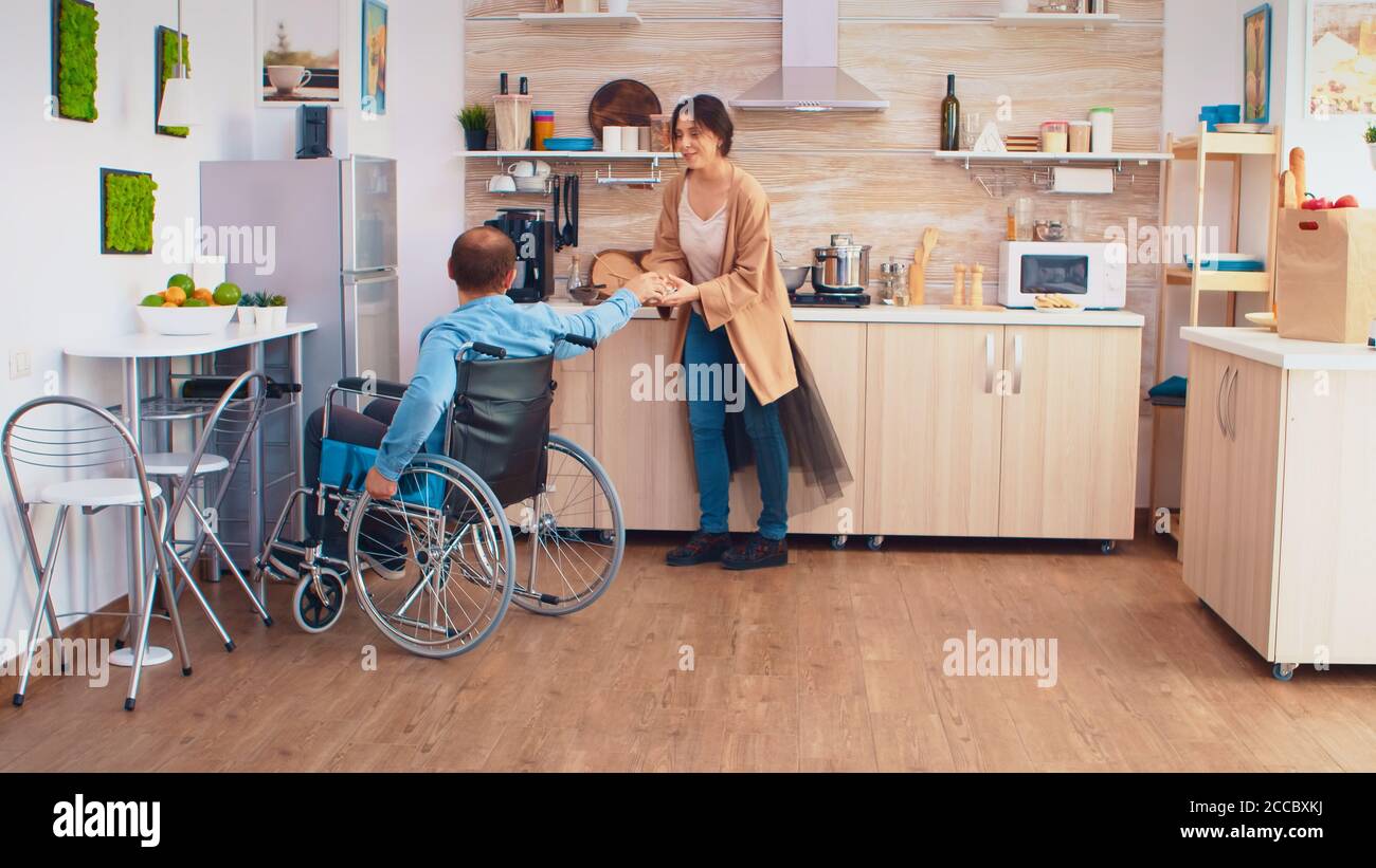 Disabled man in wheelchair opens refrigerator while wife is cooking and ...