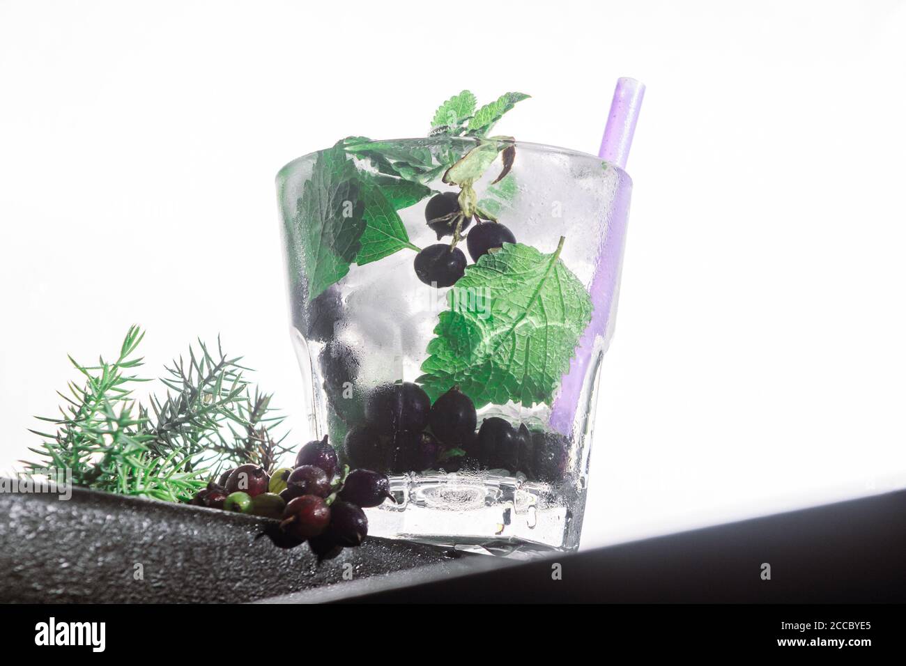 berry cocktail, mint, ice in a rox glass on the edge of a bar counter ...