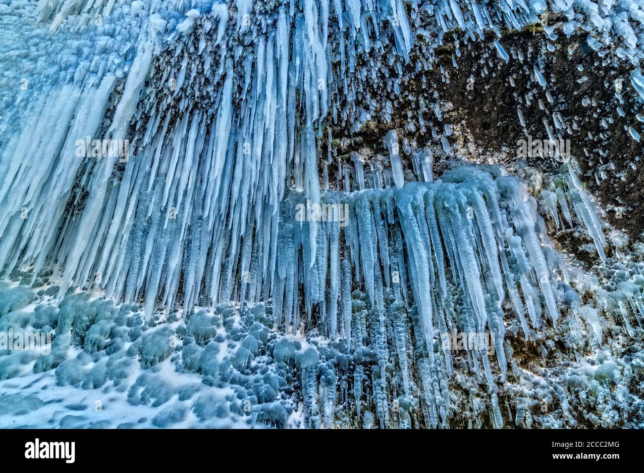 Detail of massive group of icicles on rock. Beautiful frozen water ...