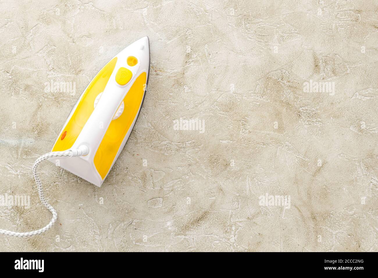 Yellow iron on ironing board. Top view, copy space Stock Photo - Alamy