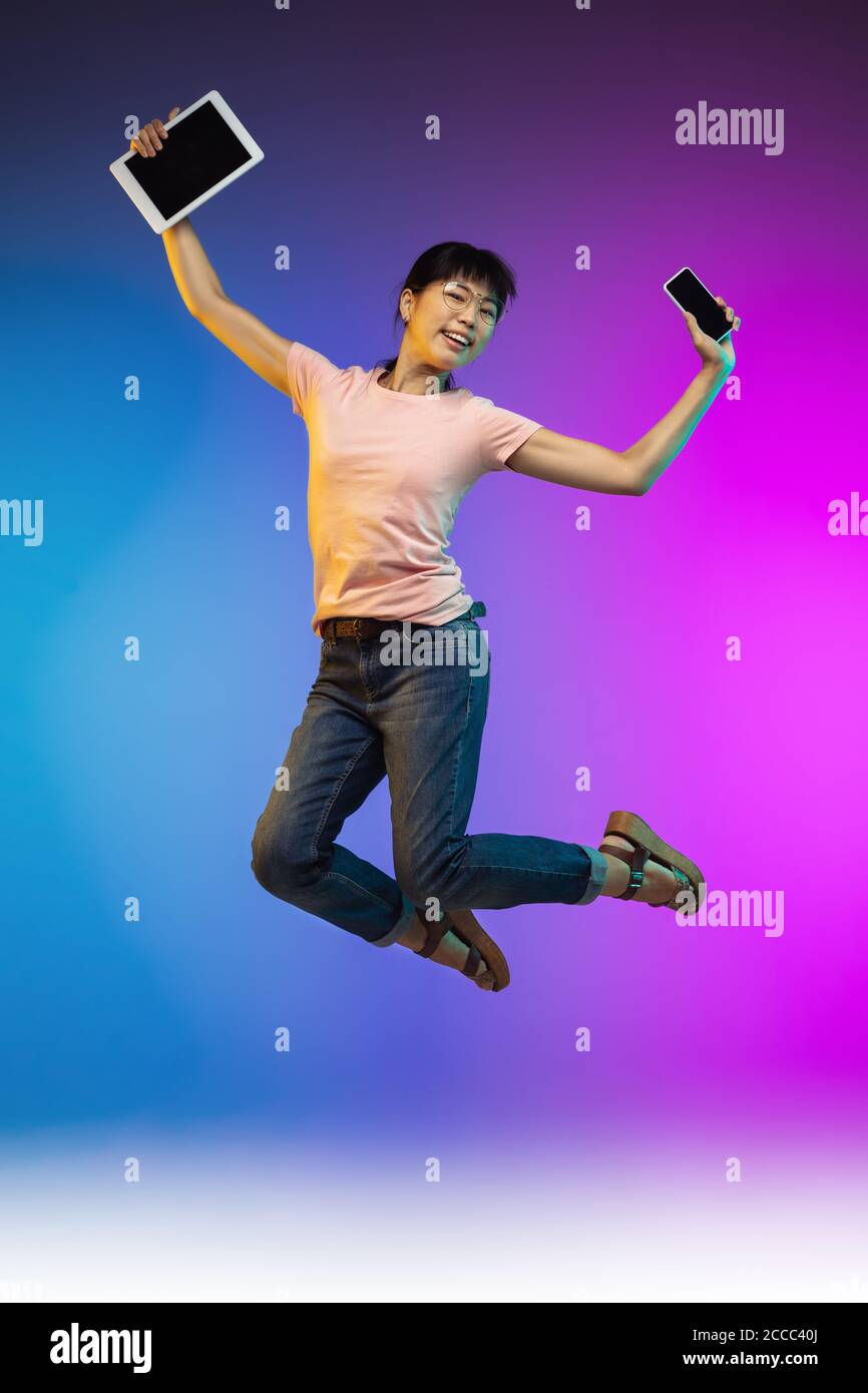 Showing devices with blank screen. Jumping high asian young woman's ...