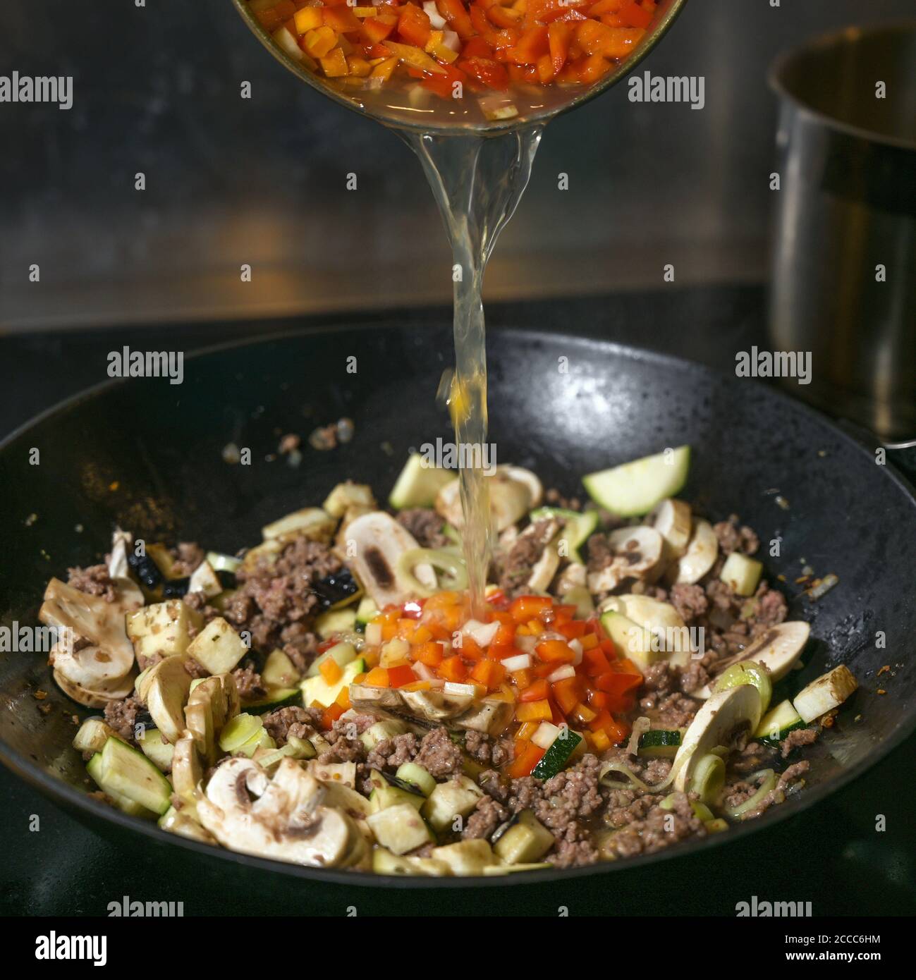 Fried minced meat and vegetables in a black cooking pan is deglazed ...