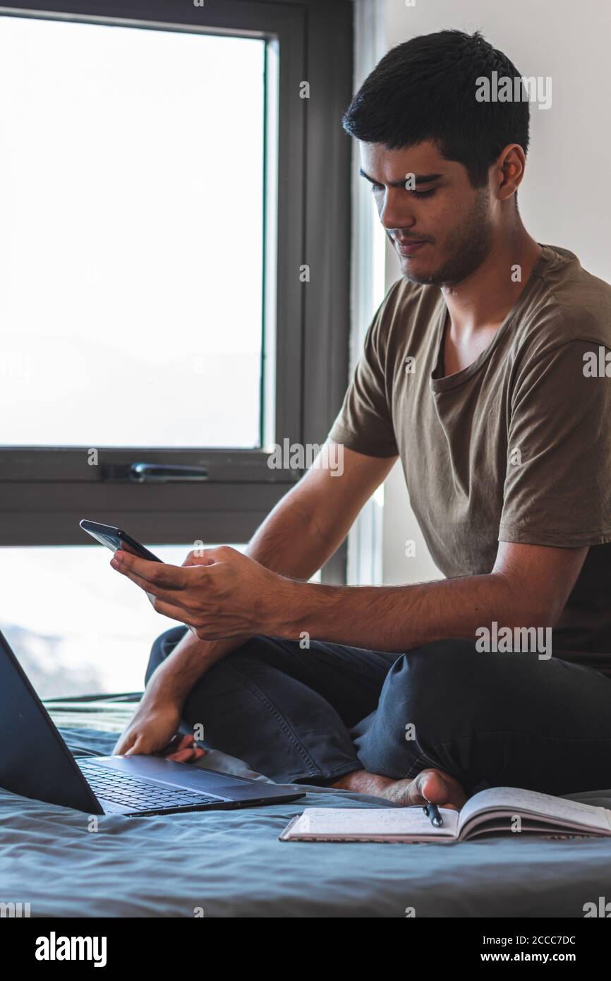 Vertical shot of a young Caucasian male studying in his room - study at ...