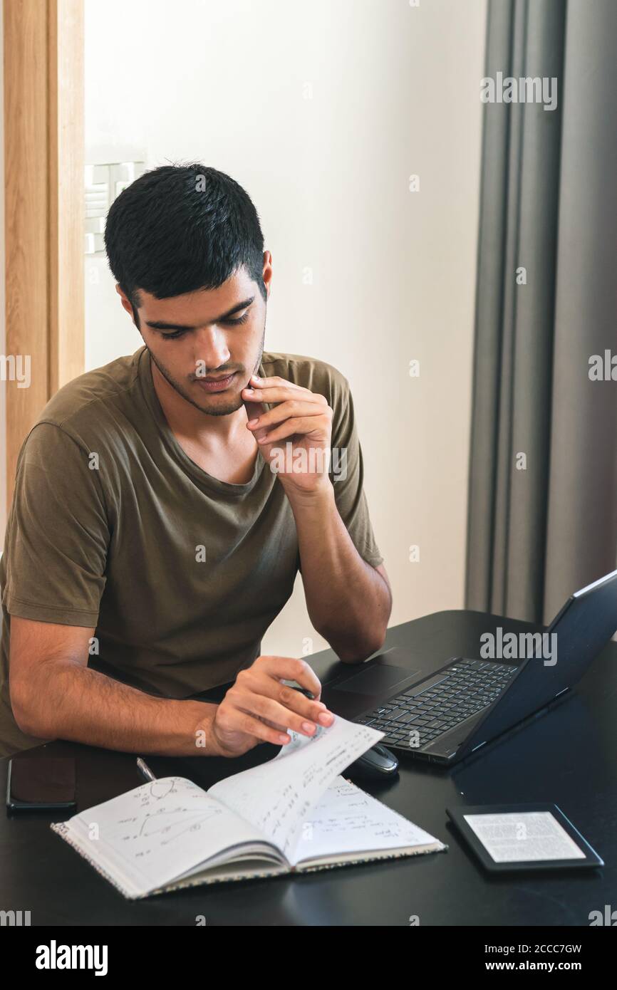 Vertical shot of a young Caucasian male studying in his room - study at ...