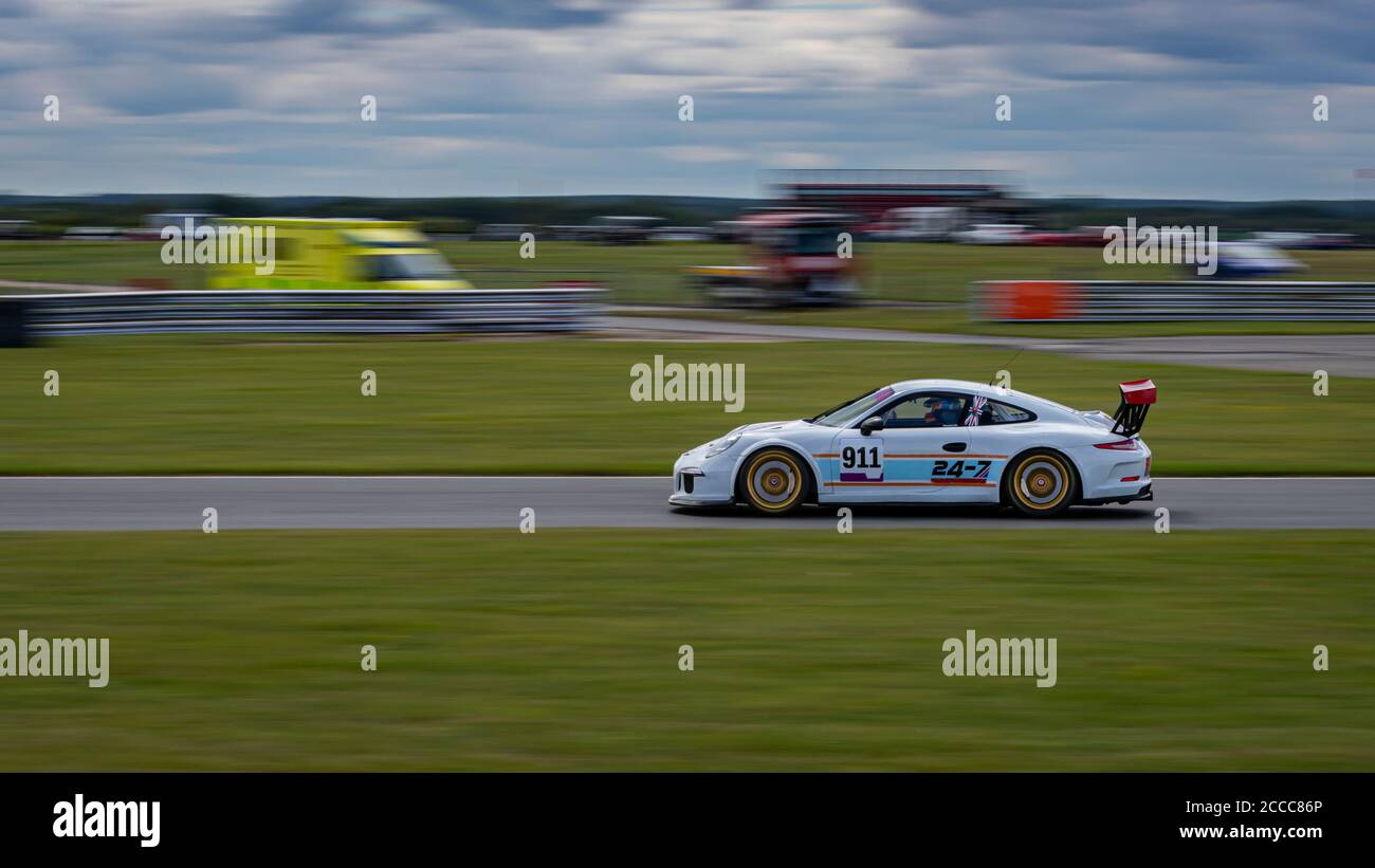 A panning shot of a white racing car as it circuits a track Stock Photo ...