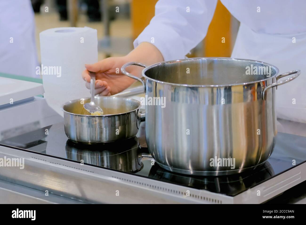 Chef hand stirring rice and millet with spoon in steel pot on electric ...