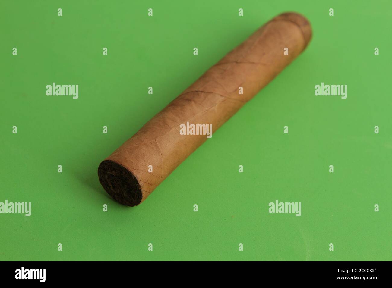 Closeup of a tobacco cigar on a green surface under the lights Stock ...