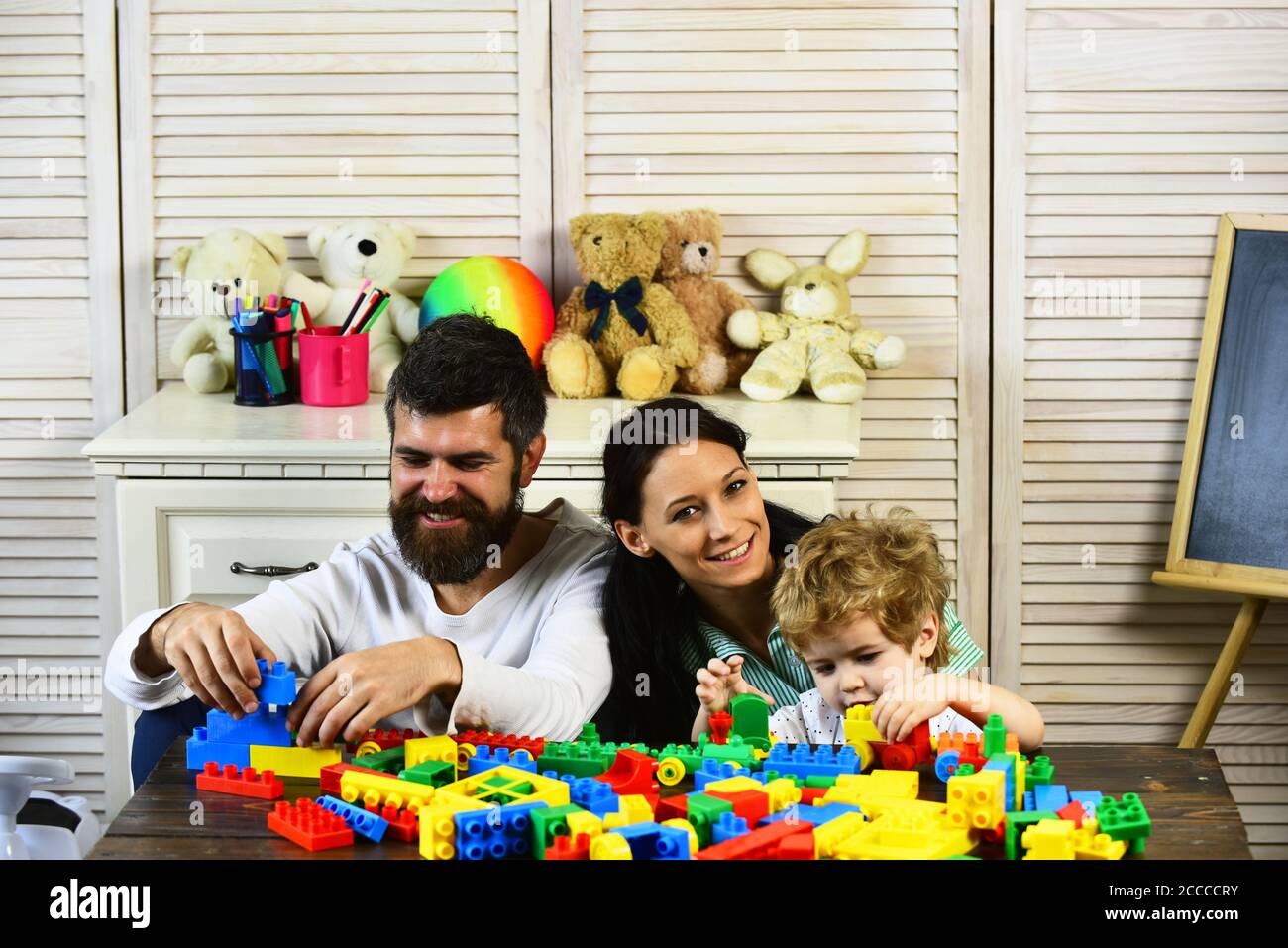 Parents and boy with smiling faces make brick constructions. Young ...