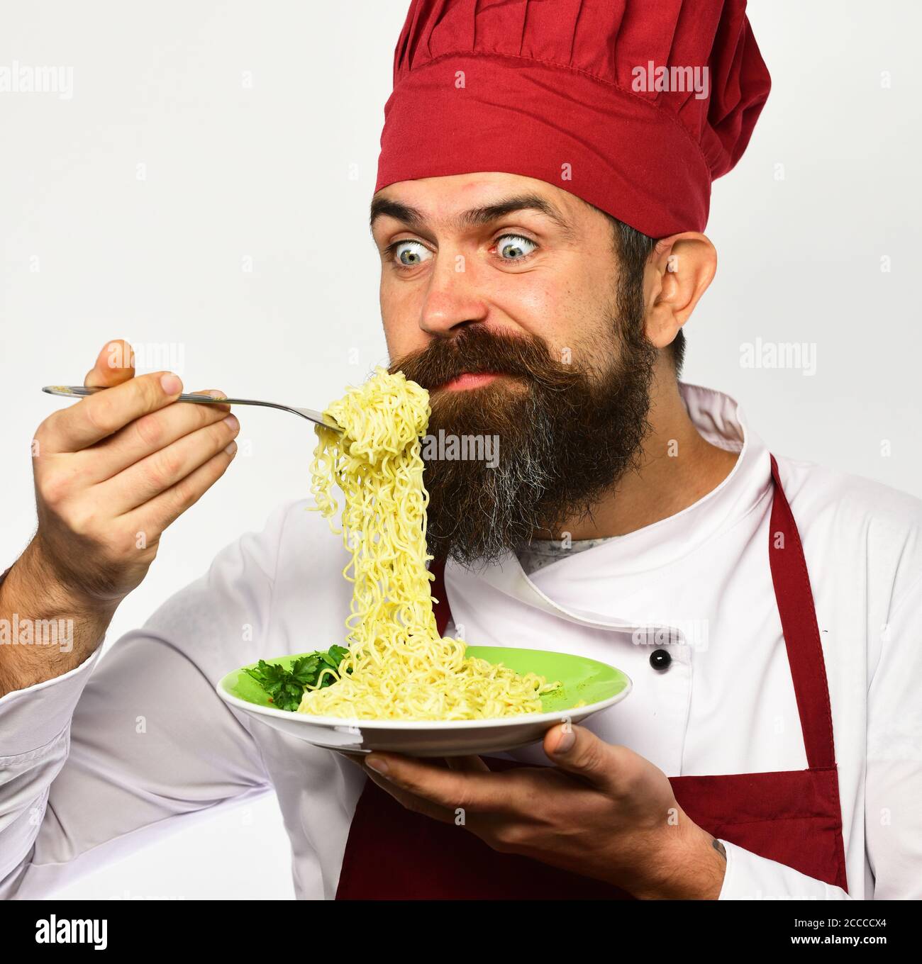Portrait of hungry cook man eating noodles over grey background, close ...