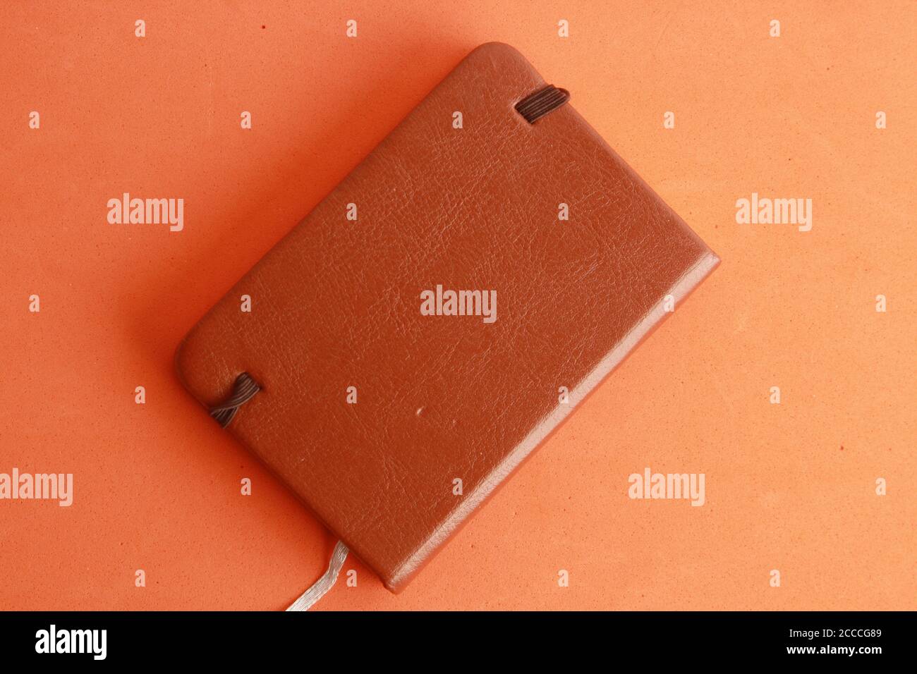 Closed brown leather notebook on an orange background Stock Photo - Alamy