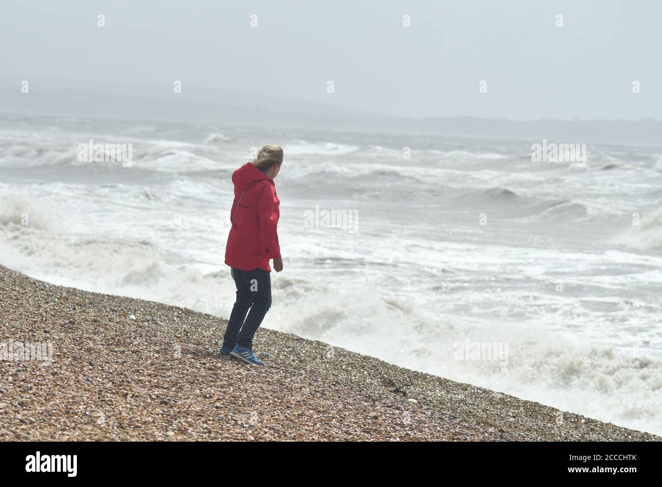 Woman leaning into strong wind at Milford-on-Sea, Hampshire, UK, August ...