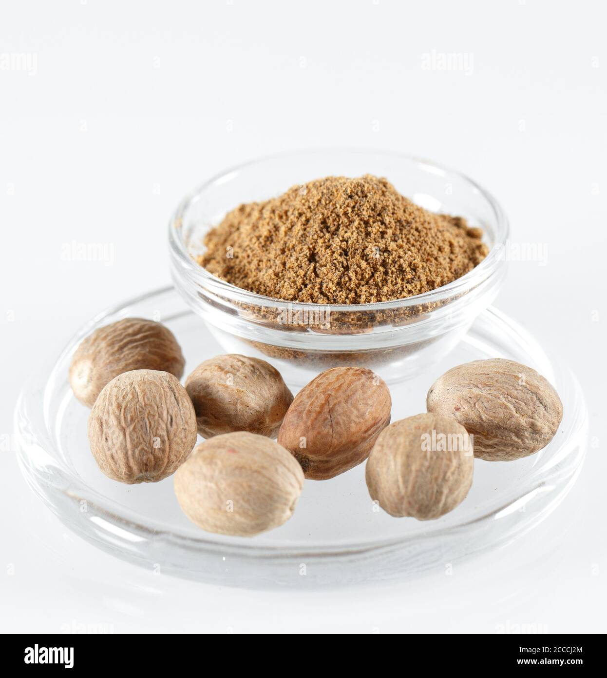 Nutmeg in a plate Isolated on a white background Stock Photo - Alamy