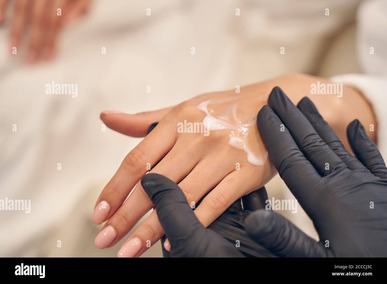 A pair of gloved hands moisturizing female skin Stock Photo - Alamy