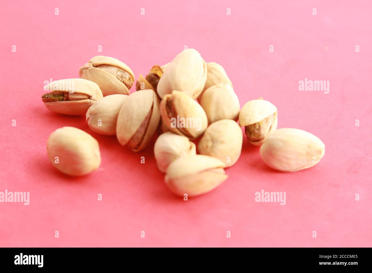 Pile of pistachios on a pink surface Stock Photo - Alamy