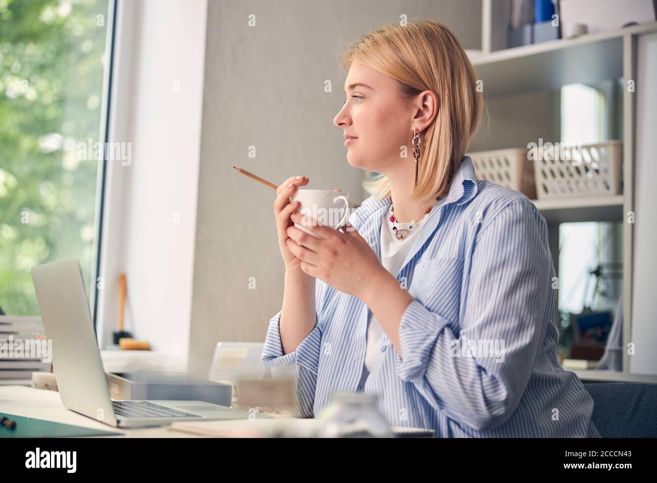 Calm woman having tea break at working table Stock Photo - Alamy