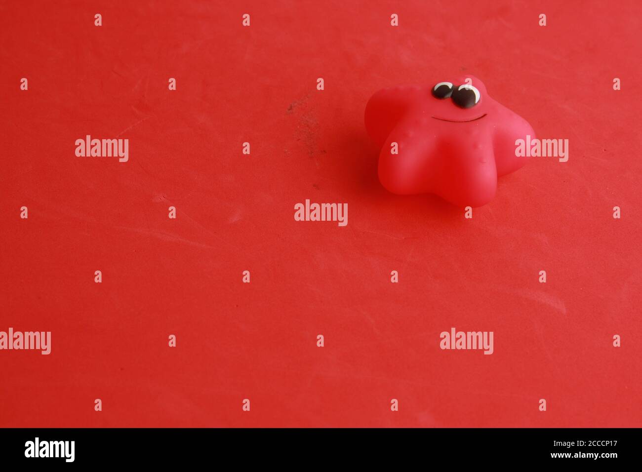 Rubber starfish toy on a red surface Stock Photo - Alamy