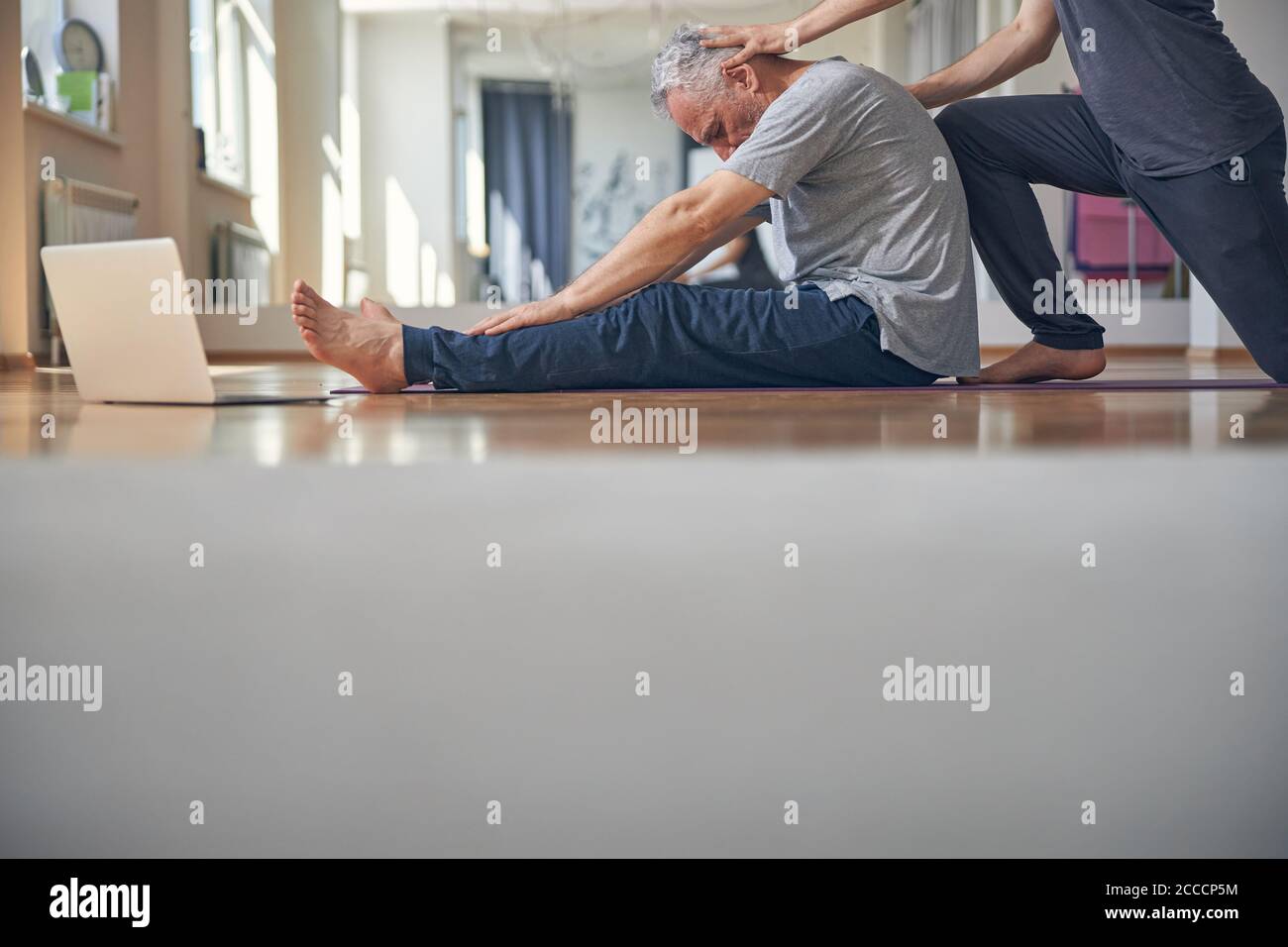 Caucasian man doing a seated forward bend Stock Photo - Alamy